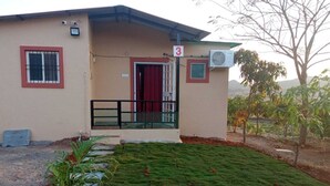 Um edifício com uma porta vermelha, uma placa com o número 3 e um pequeno alpendre com guarda-corpo preto.