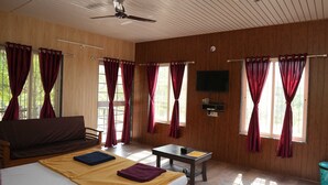 Um quarto com cama, sofá, mesa e televisão.