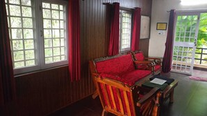 Um quarto com painéis de madeira, um sof á vermelho, um banco de madeira e um ventilador de teto.