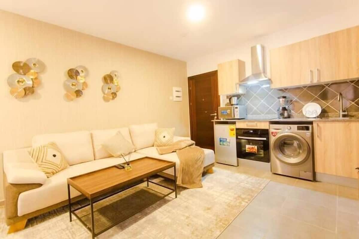 Um espaço compacto com sofá, mesa de centro e máquina de lavar.