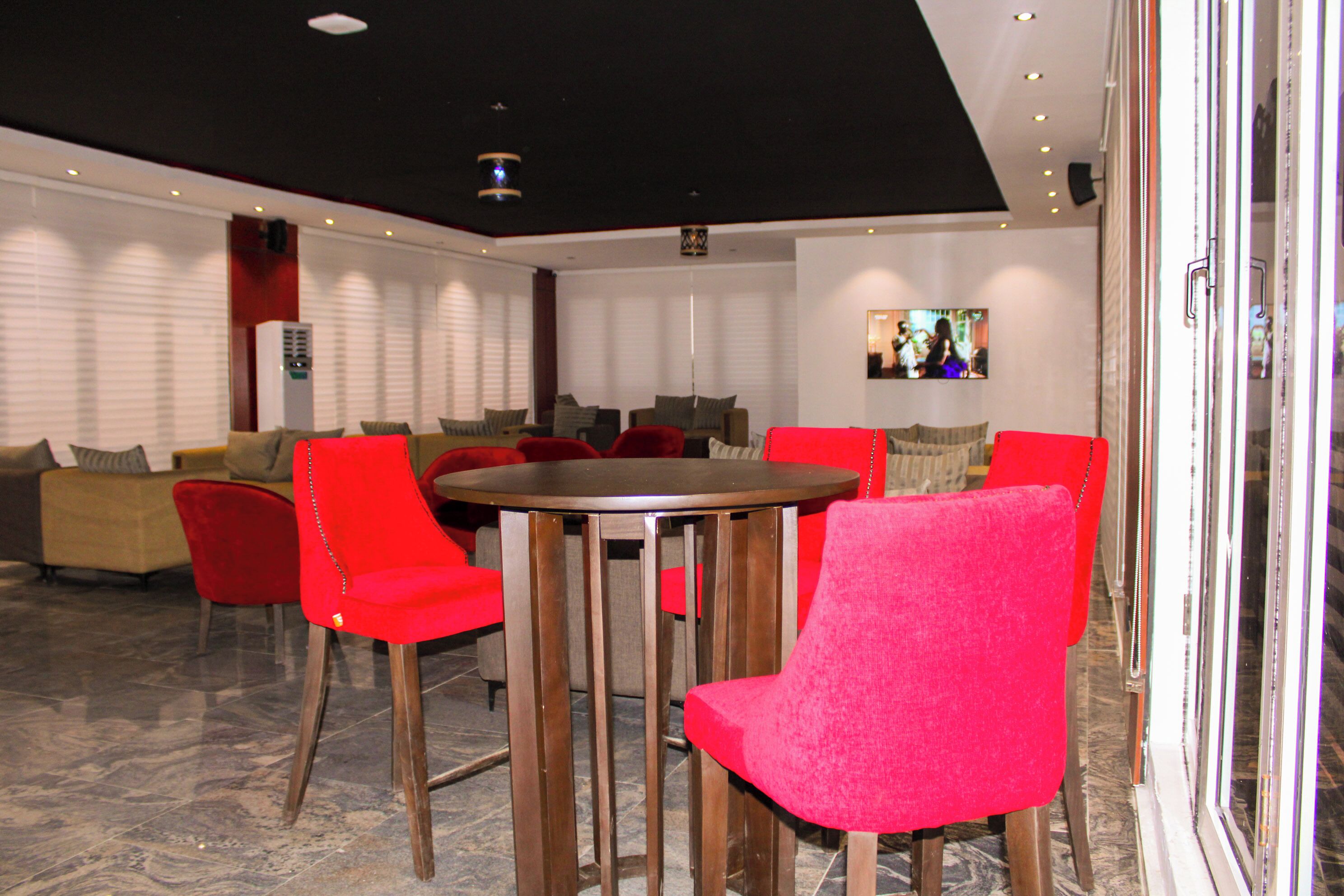 Uma sala de estar moderna com uma mesa redonda, cadeiras vermelhas e um sofá.