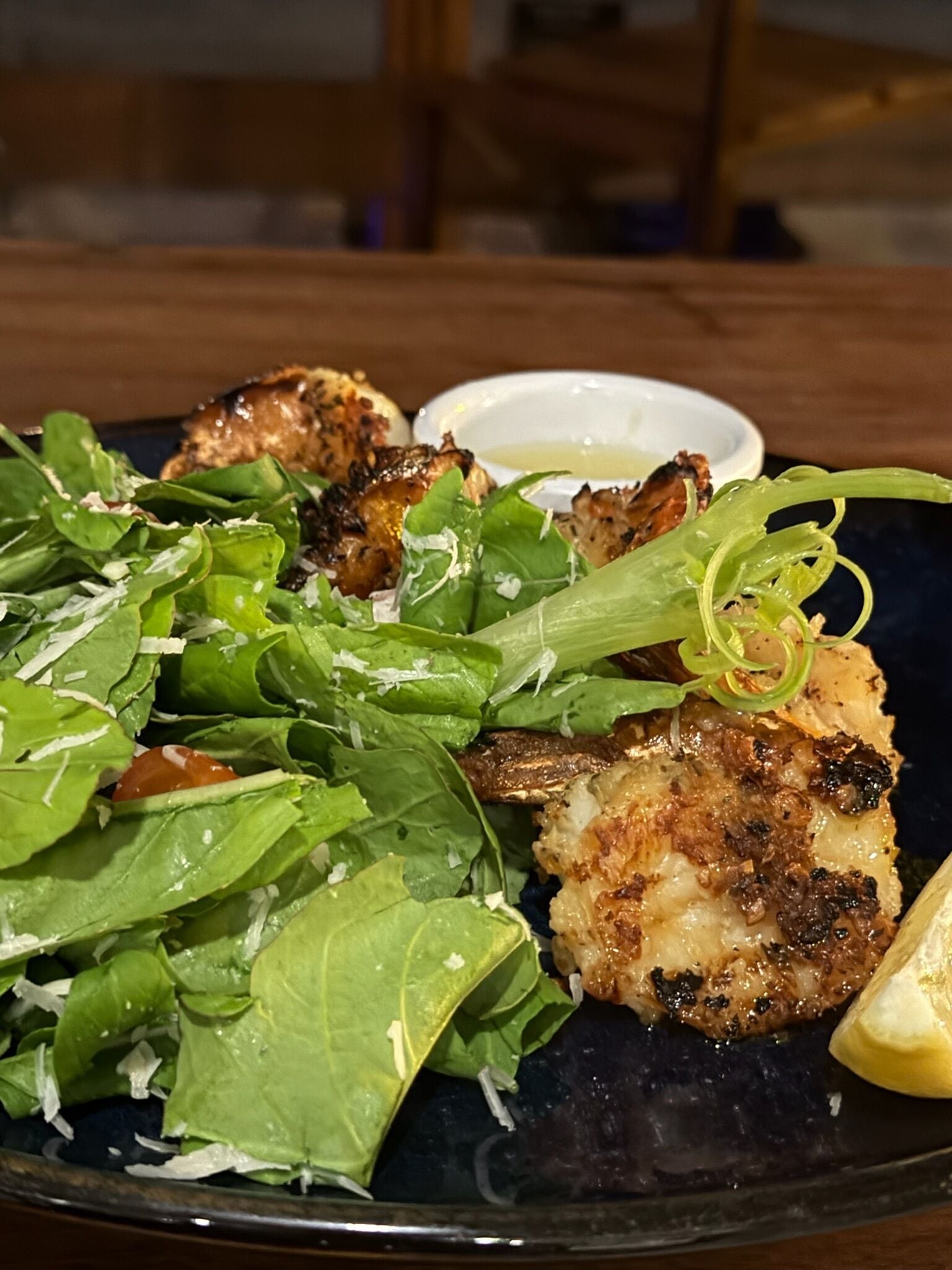 Prato com frango grelhado, vegetais verdes e uma fatia de limão.