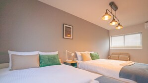 Quarto de hotel com duas camas, um quadro na parede e uma janela com persianas.