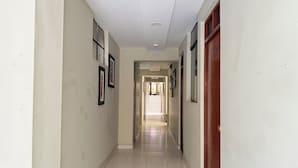 Um corredor comprido e estreito, com chão de azulejos e paredes brancas.