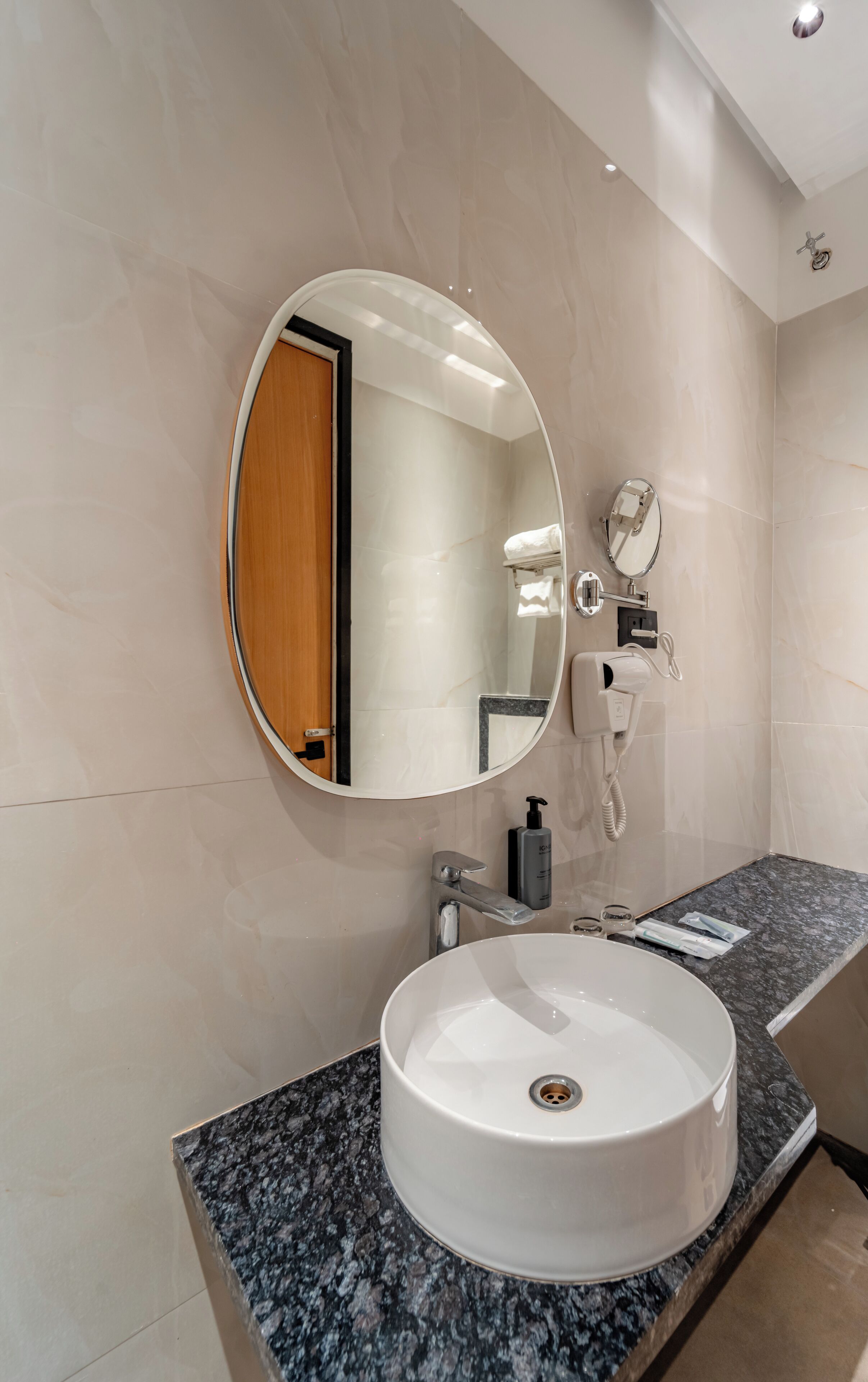 Uma casa de banho moderna com uma sanita redonda, um espelho grande e um secador de cabelo.