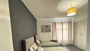 Quarto com duas camas, um guarda-roupa grande e um quadro na parede.