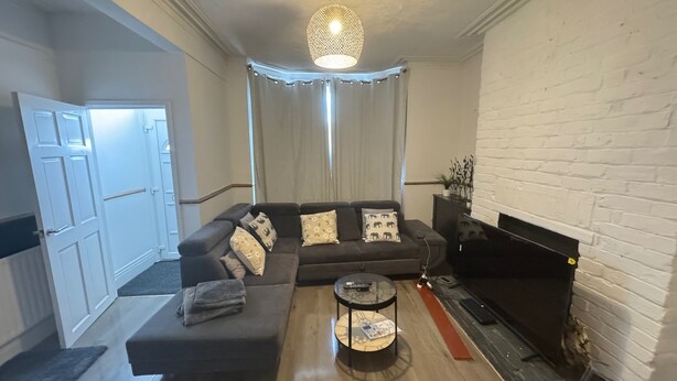 Uma sala de estar com sofá, mesa de centro, televisão e lareira.
