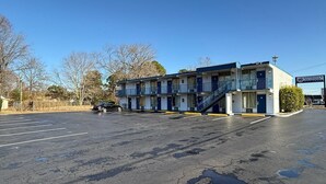 Um motel com vários andares, um estacionamento, uma escadaria que leva à entrada e um letreiro.