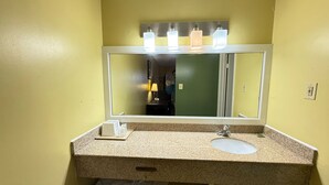 Casa de banho com bancada de granito, pia, espelho e suporte para toalhas.