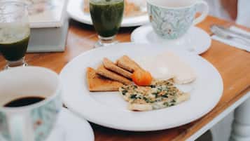 Uma mesa com torradas, tomate, ovos mexidos e um smoothie verde.