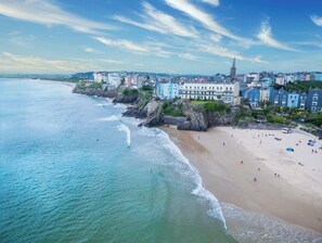 Uma cidade costeira com praia, edifícios e uma torre de igreja imponente.