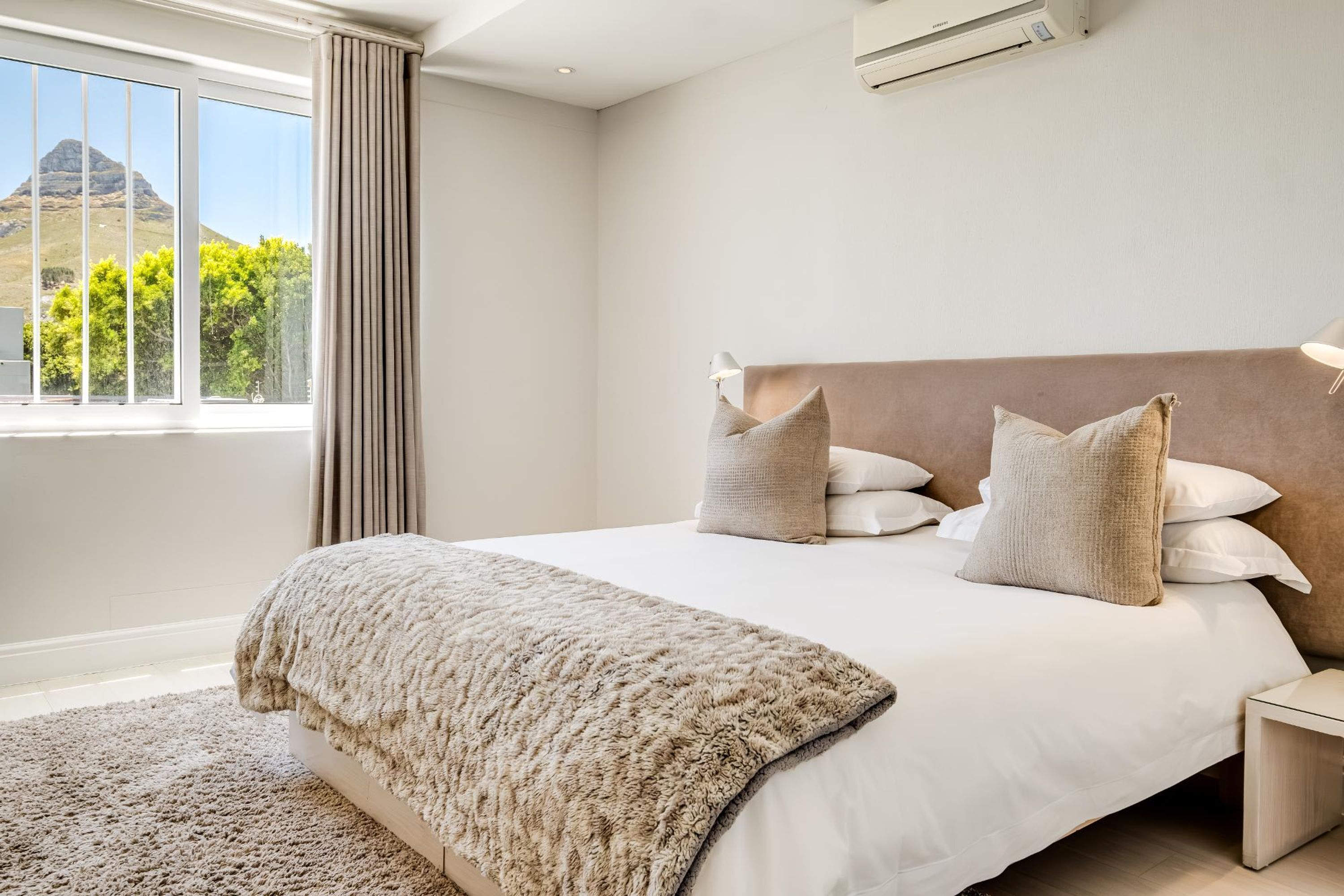 Quarto com uma cama grande, vista para uma montanha e janela com cortinas.