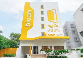 Um edifício de hotel moderno com uma coloração marcante em amarelo e branco, exibindo os nomes 'bloom' e 'bloom hotel' na fachada.