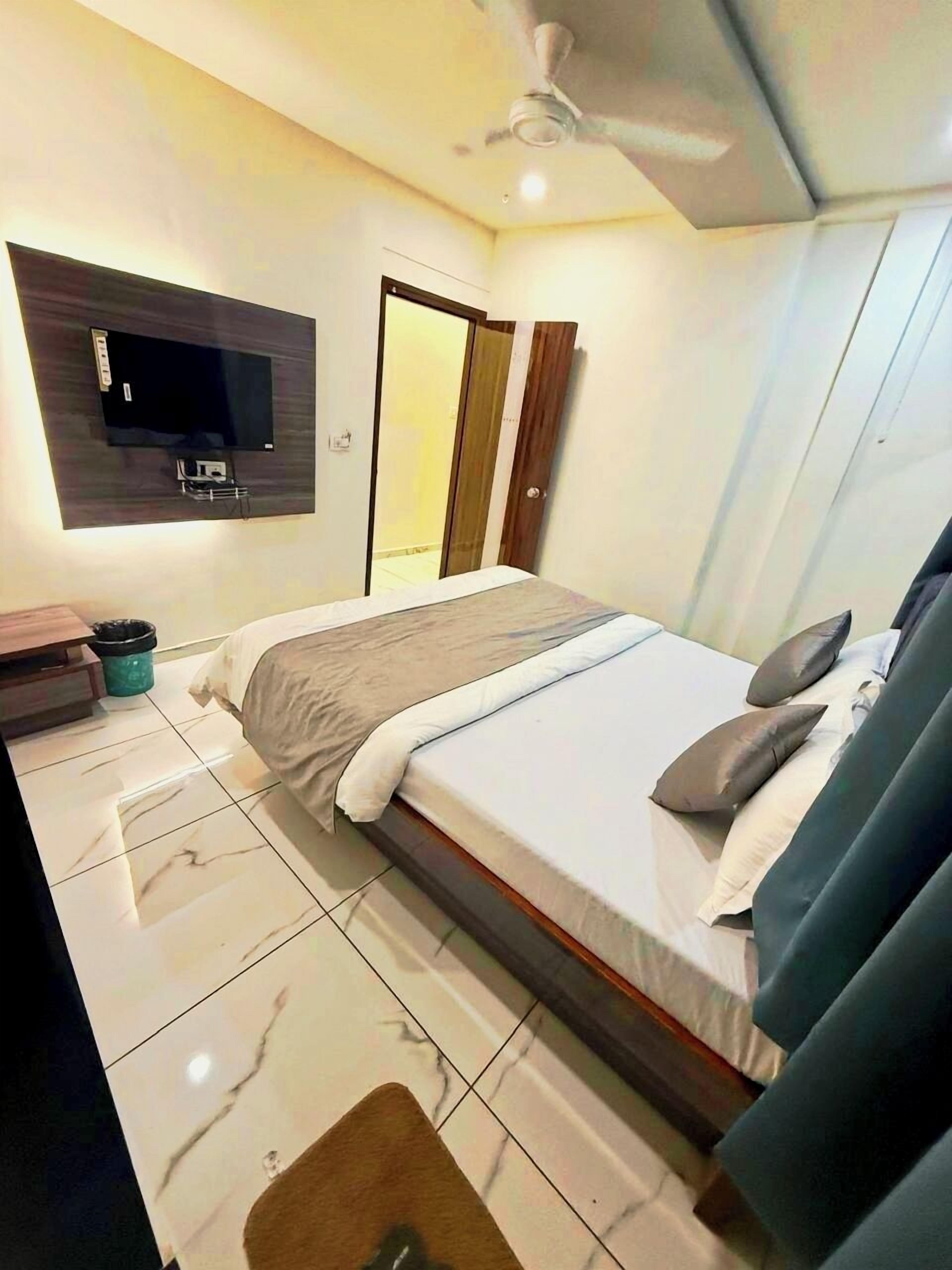 Quarto moderno com cama, televisão fixada na parede, porta e ventilador de teto.