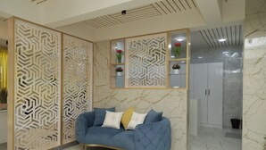 Uma sala de estar moderna com um sofá azul, painéis decorativos e piso de mármore.