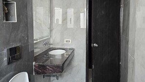 Uma casa de banho moderna com sanita, lavatório e espelho.