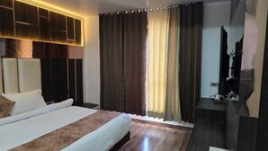 Quarto de hotel com uma cama grande, uma escrivaninha e um espelho.