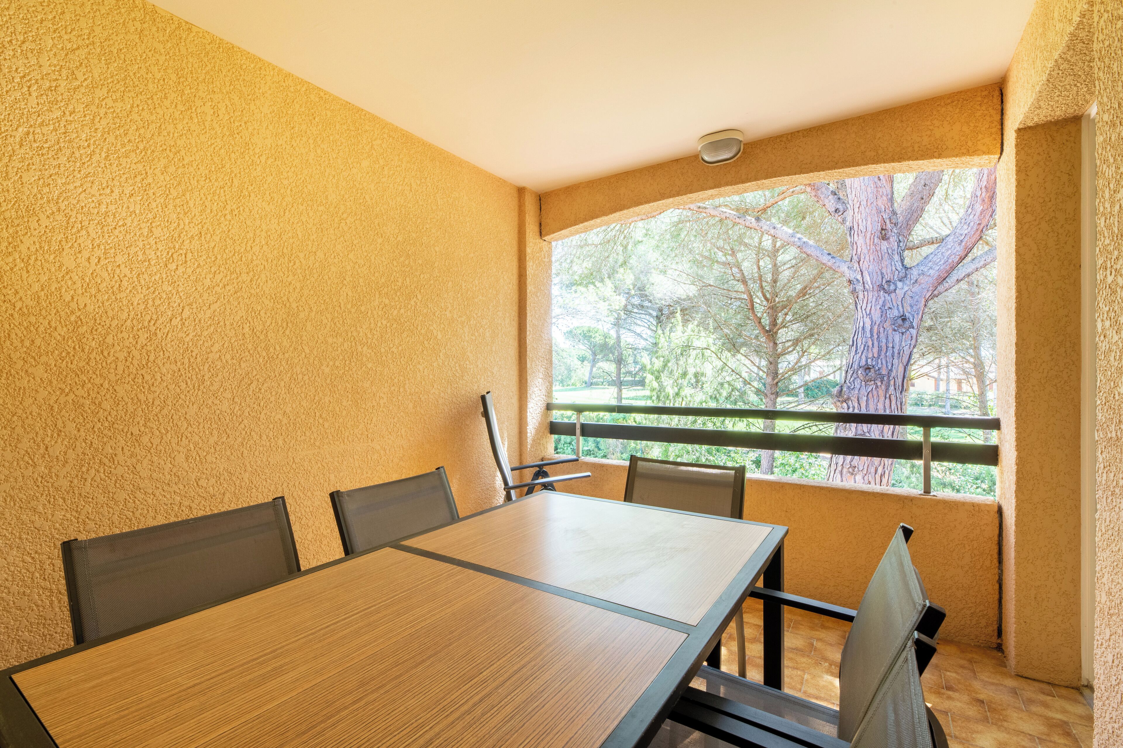 Uma sala de conferências com uma mesa e cadeiras de madeira, uma janela com vista para árvores e uma varanda com corrimão.