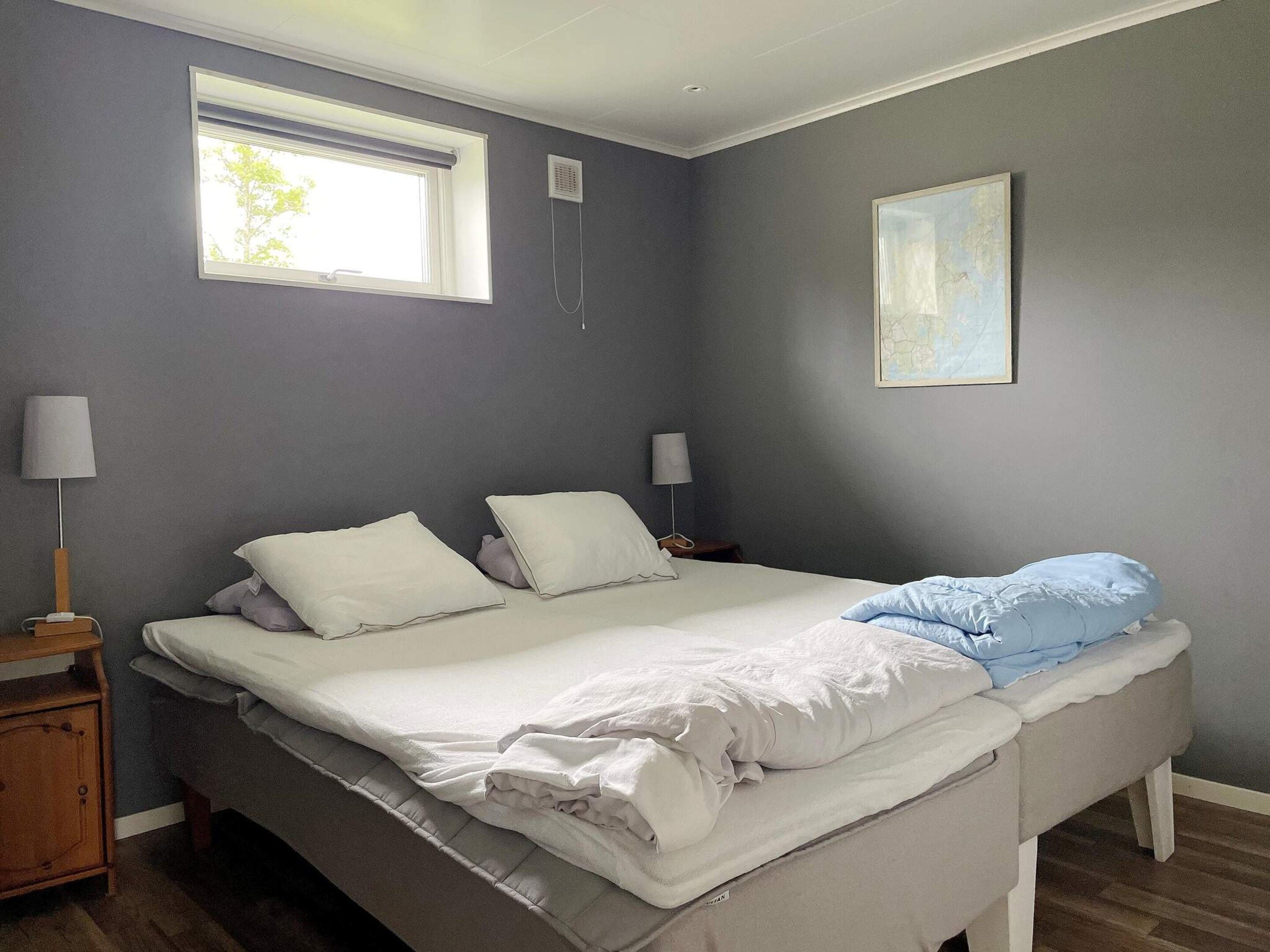 Quarto com cama, duas mesas de cabeceira, janela e purificador de ar fixado na parede.
