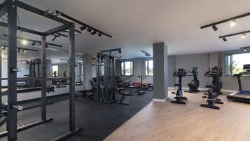Uma academia moderna com diversos equipamentos de exercício, incluindo um suporte para agachamento, aparelhos de musculação e equipamentos de cardio.