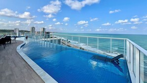 Piscina infinita no terraço com vista para o oceano e o horizonte da cidade.