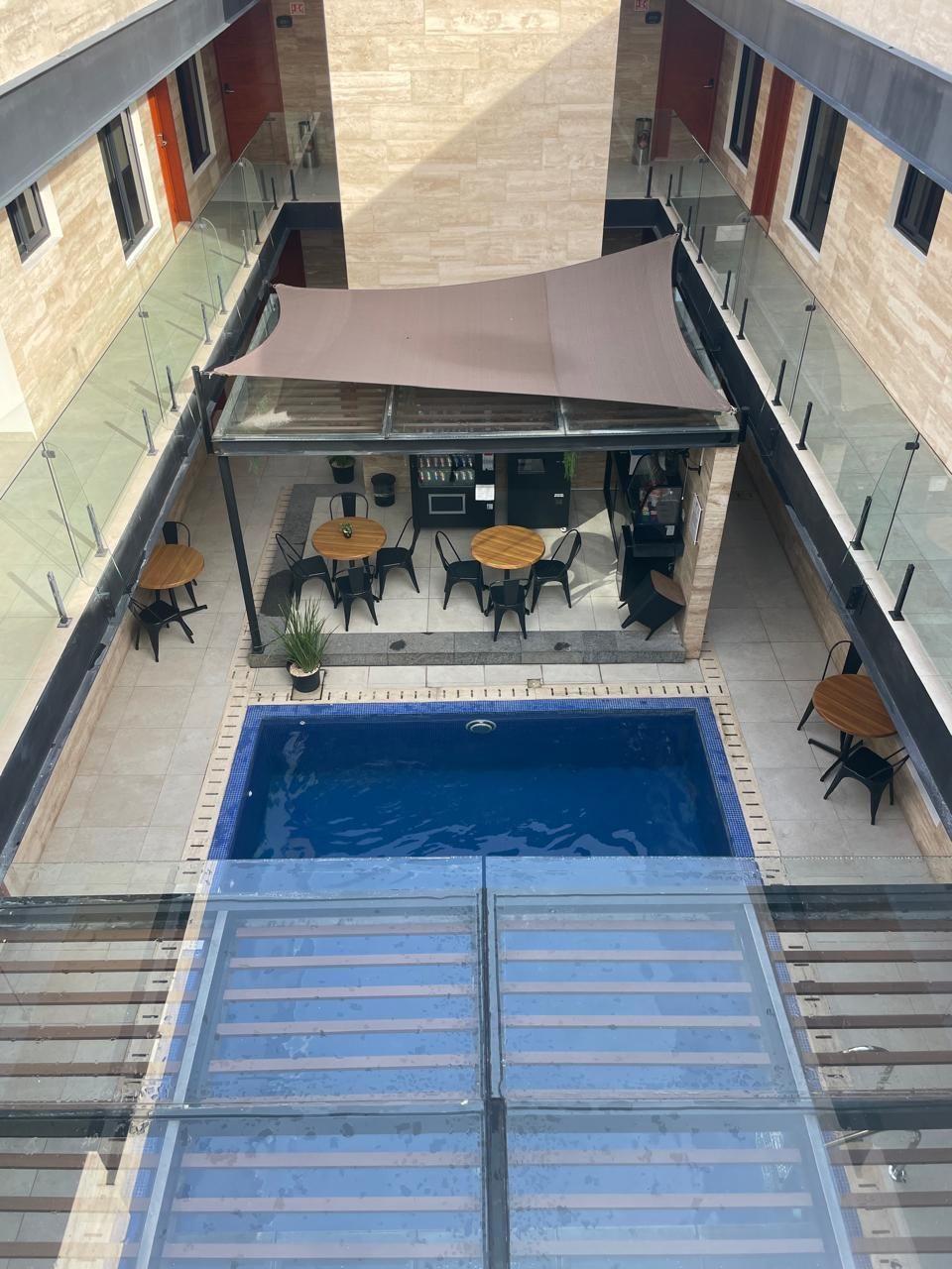 Área de piscina no terraço, com espaço de estar coberto e piscina.