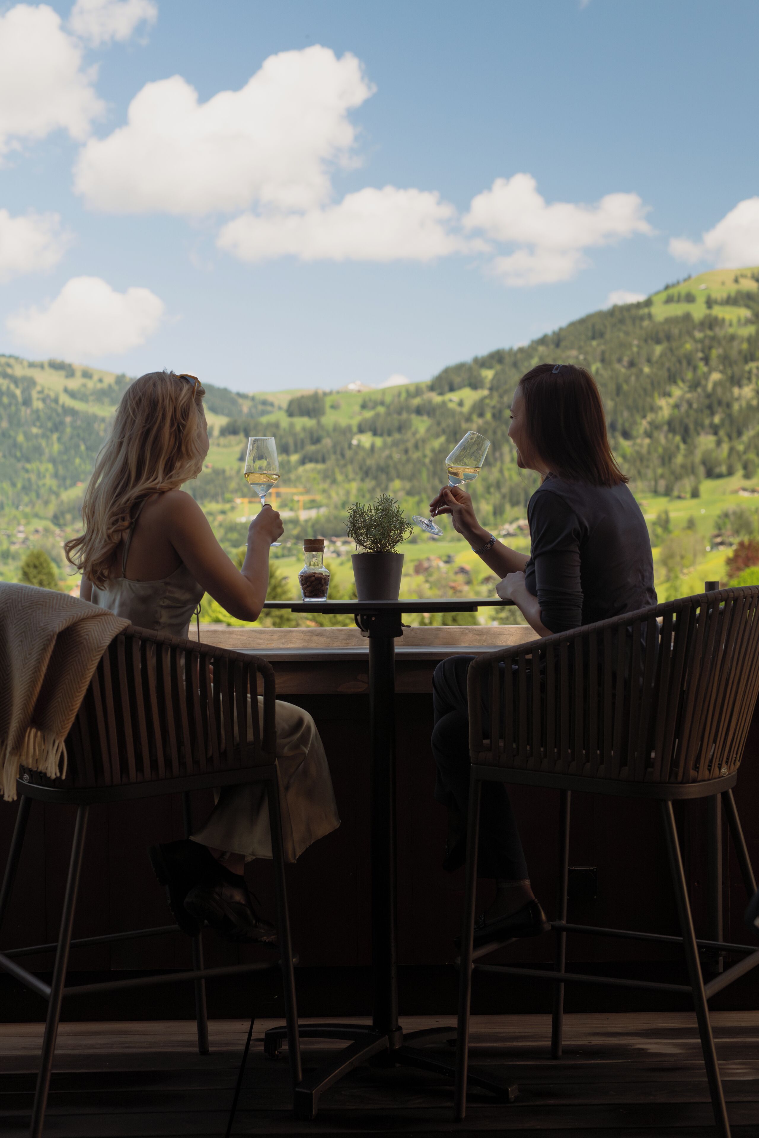 Duas pessoas sentadas a uma mesa com vista para uma paisagem verde.