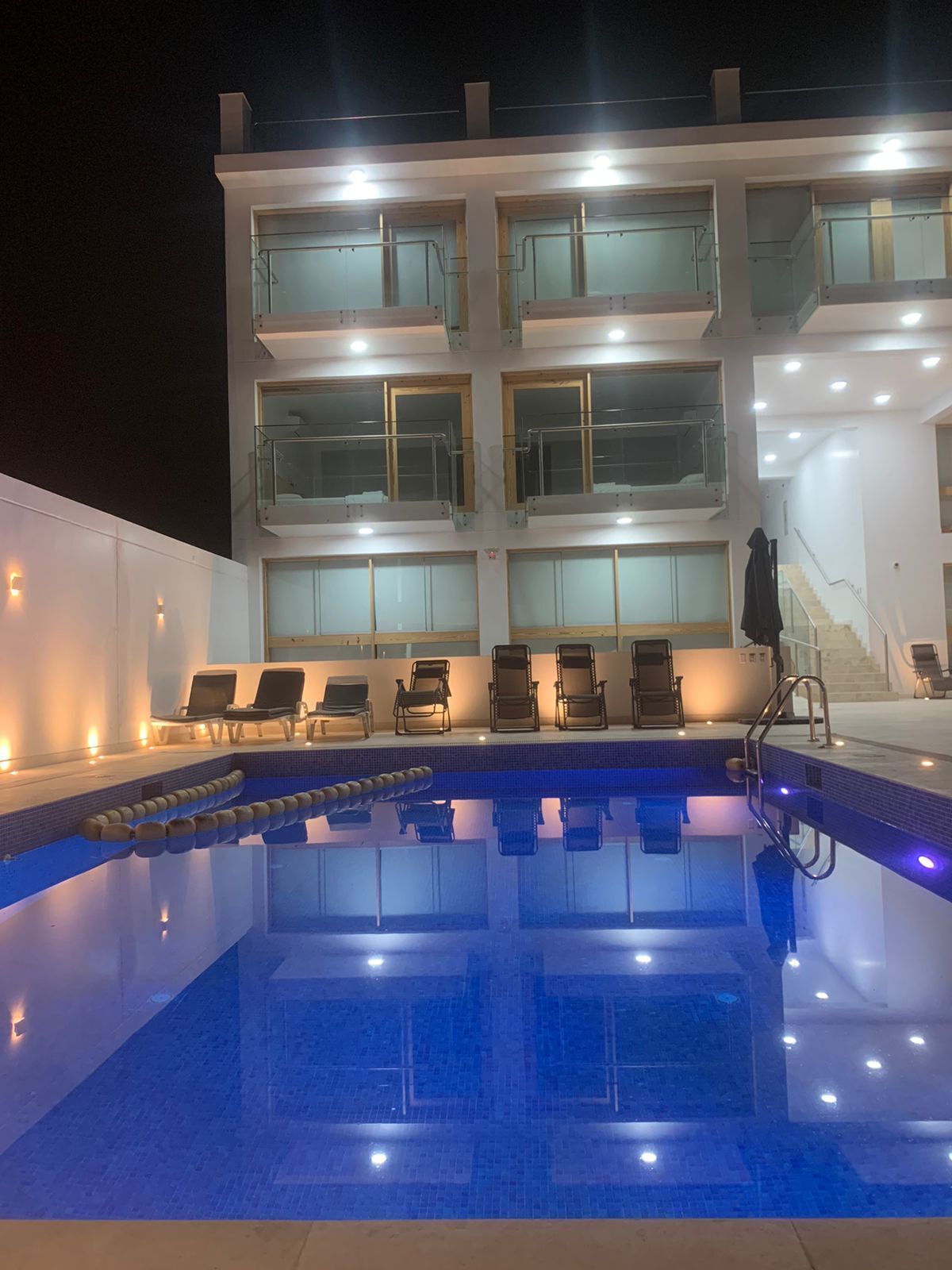 Uma área de piscina em vários níveis, com espreguiçadeiras e uma escadaria que dá acesso a um andar superior.