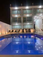 Uma área de piscina em vários níveis, com espreguiçadeiras e uma escadaria que dá acesso a um andar superior.