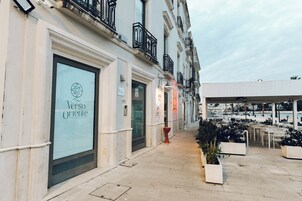 Uma rua com fachadas de lojas, incluindo uma placa visível para 'Verso Oriente'.