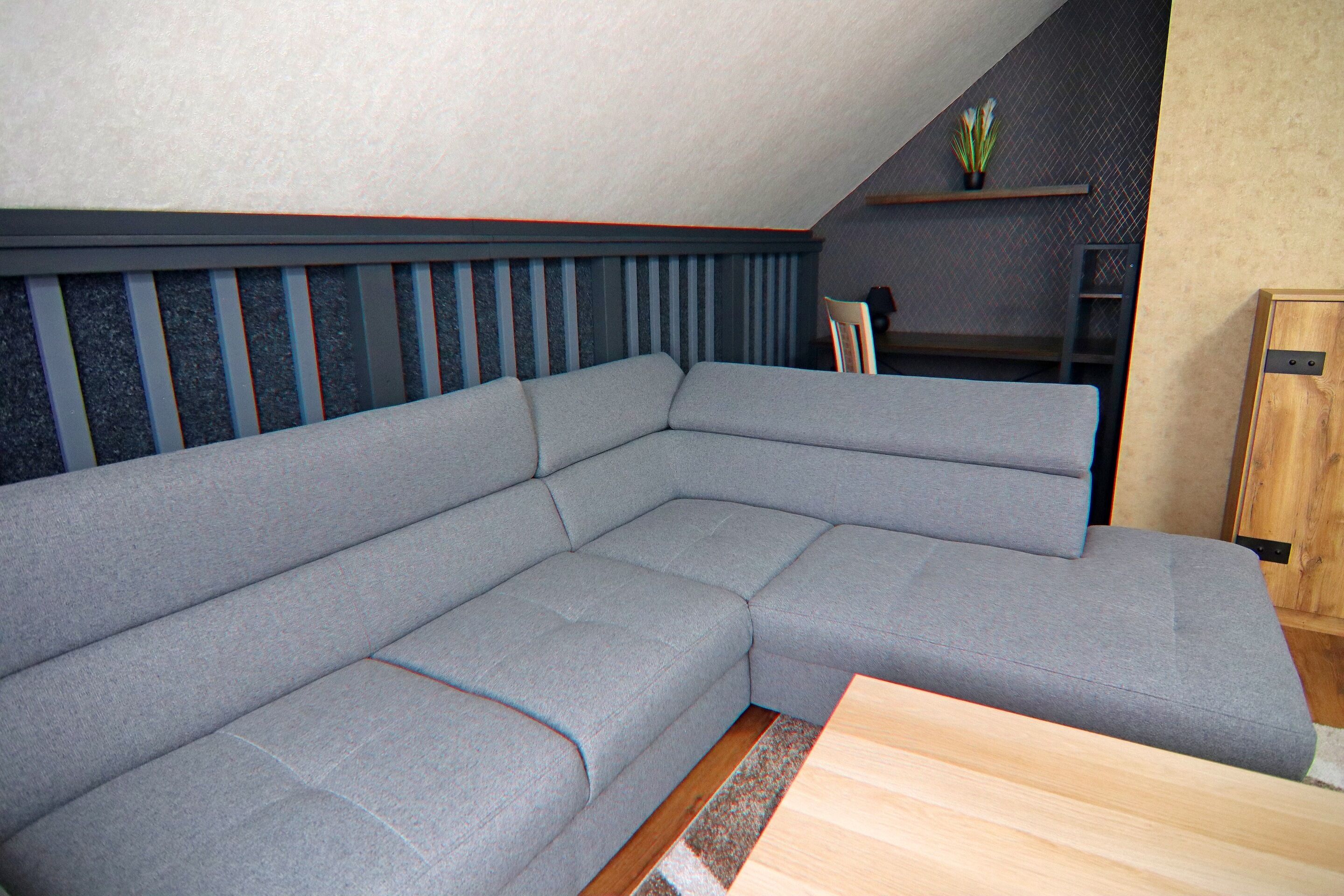 Uma sala de estar moderna com um sofá modular cinza, piso de madeira e uma pequena mesa de madeira.