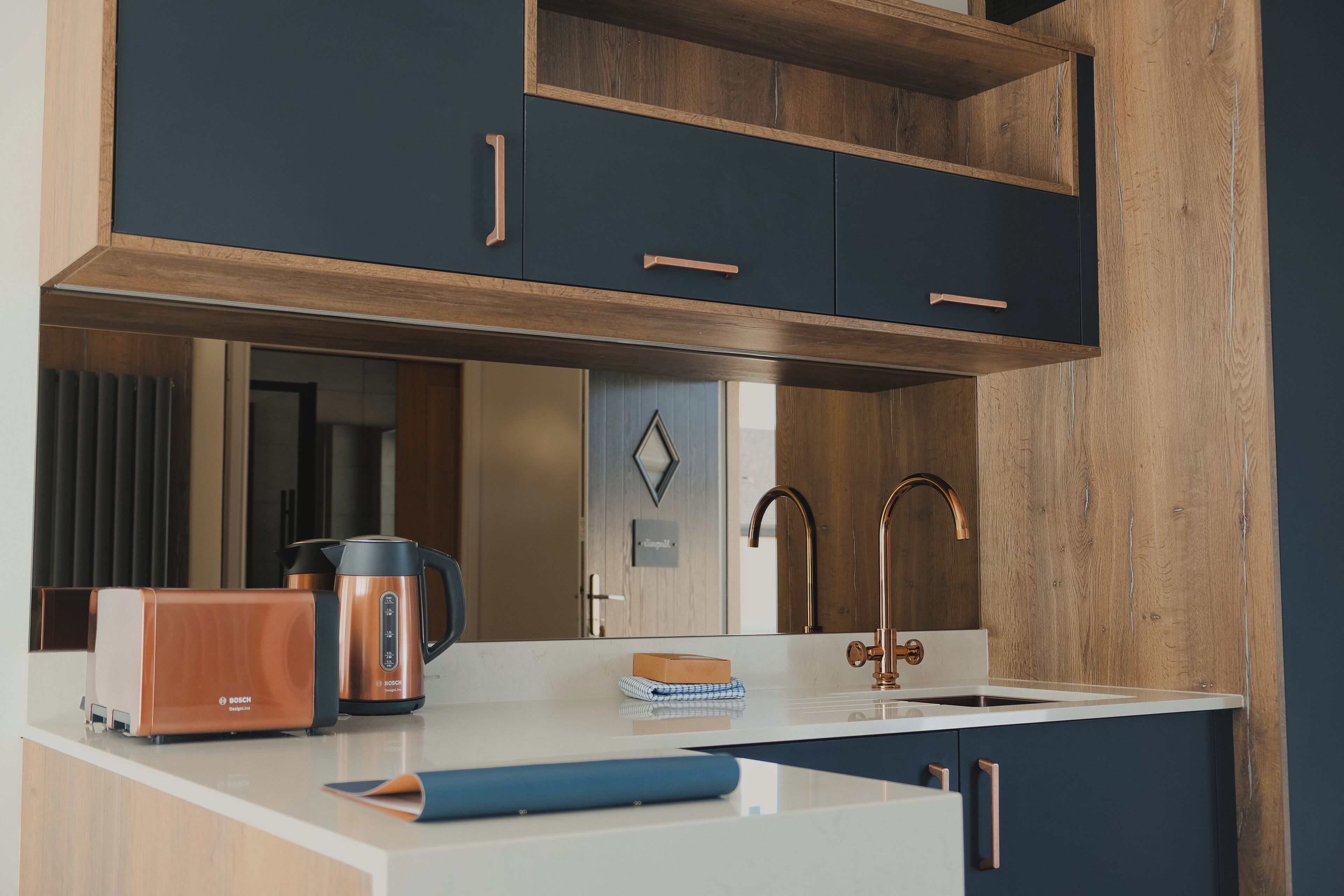 Uma cozinha moderna com uma torradeira Bosch, uma cafeteira e uma pia com torneira de cobre.