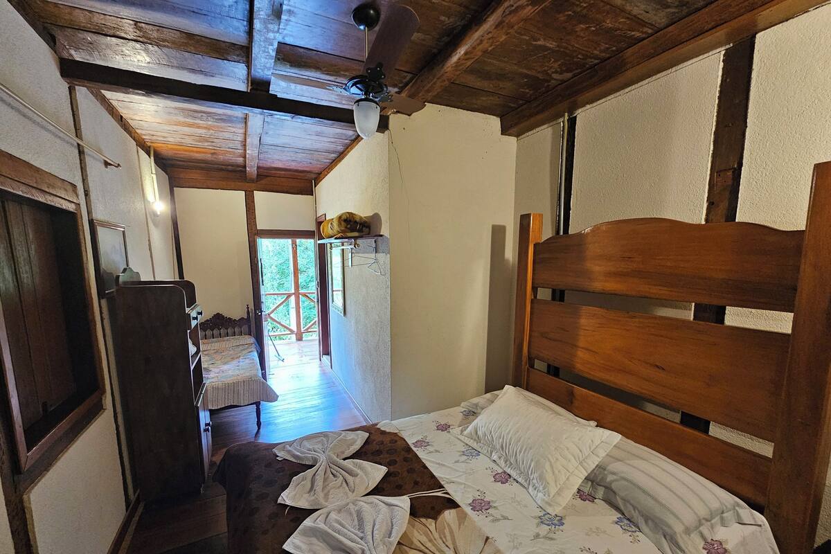 Quarto pequeno com teto de madeira e cama com roupa de cama florida.