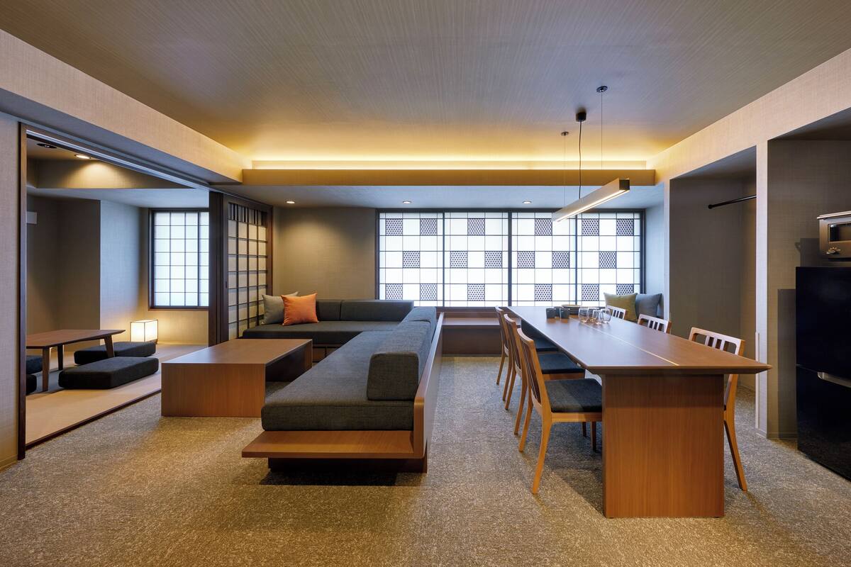 Uma sala de estar moderna com sofá, mesa de jantar e cadeiras. Há uma janela grande com vista para o exterior.