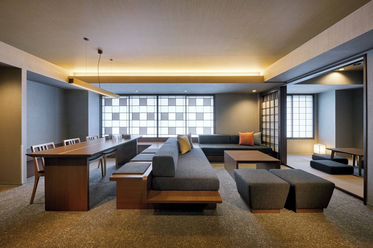 Uma sala de reunião moderna com uma mesa comprida, sofás e uma grande janela com vista.