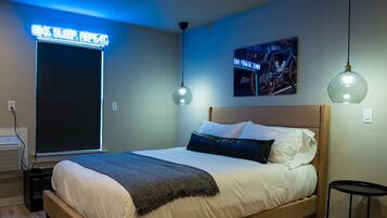 Quarto com cama, janela, ar-condicionado fixado na parede e letreiro luminoso.