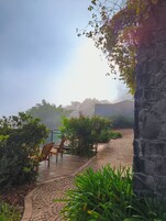 Um espaço ao ar livre com um deck de madeira, uma parede de pedra e vista para a paisagem circundante.