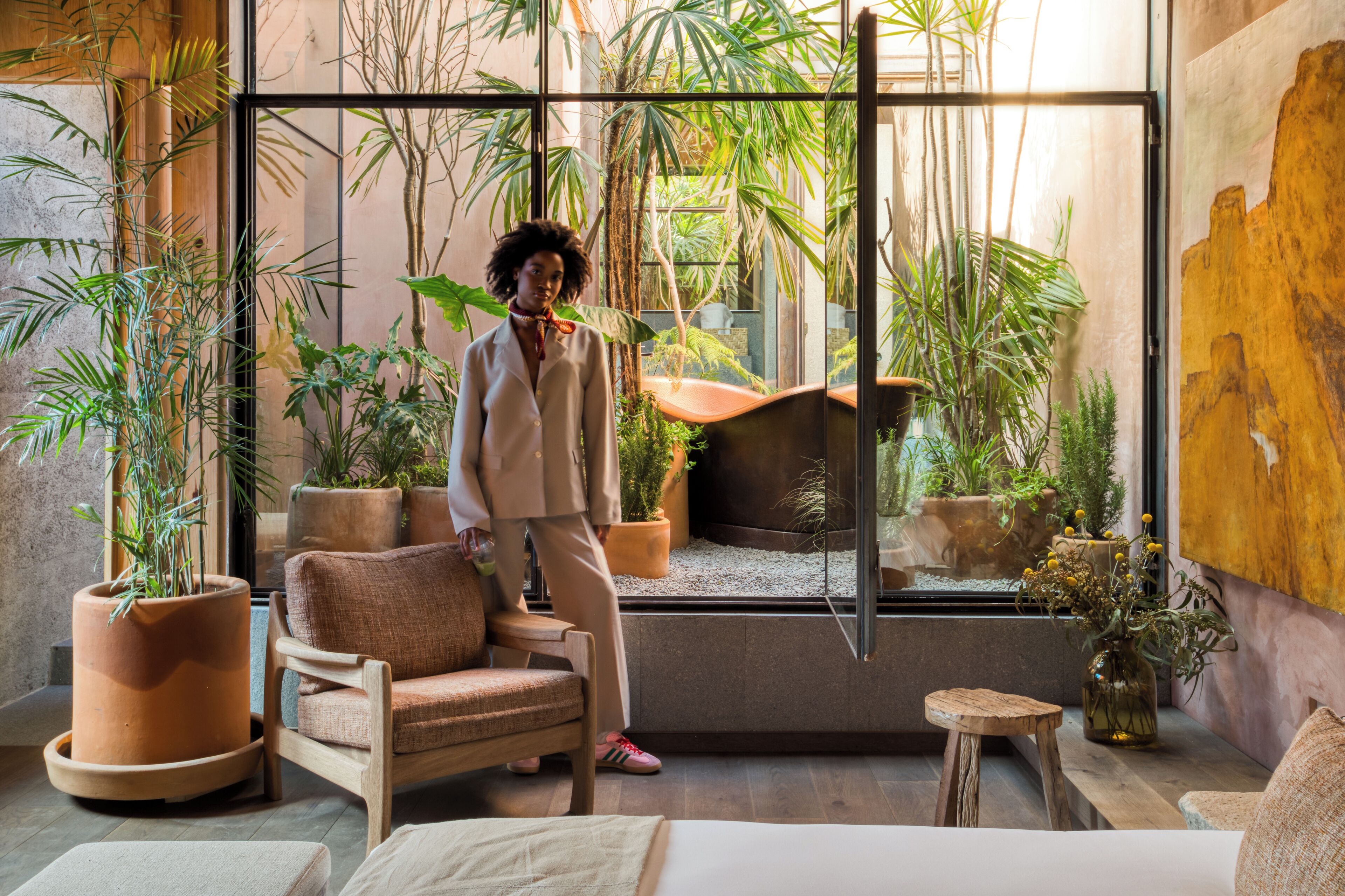 Um interior moderno com uma janela ampla, móveis de madeira e vários vasos de plantas.