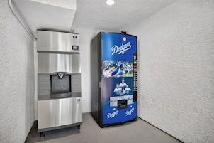 Máquina de vendas com painel azul decorado com o tema do time Dodgers e um distribuidor de bebidas em aço inoxidável.
