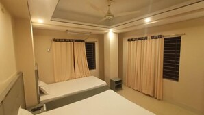 Quarto de hotel com duas camas de solteiro, um ventilador de teto e uma mesinha.
