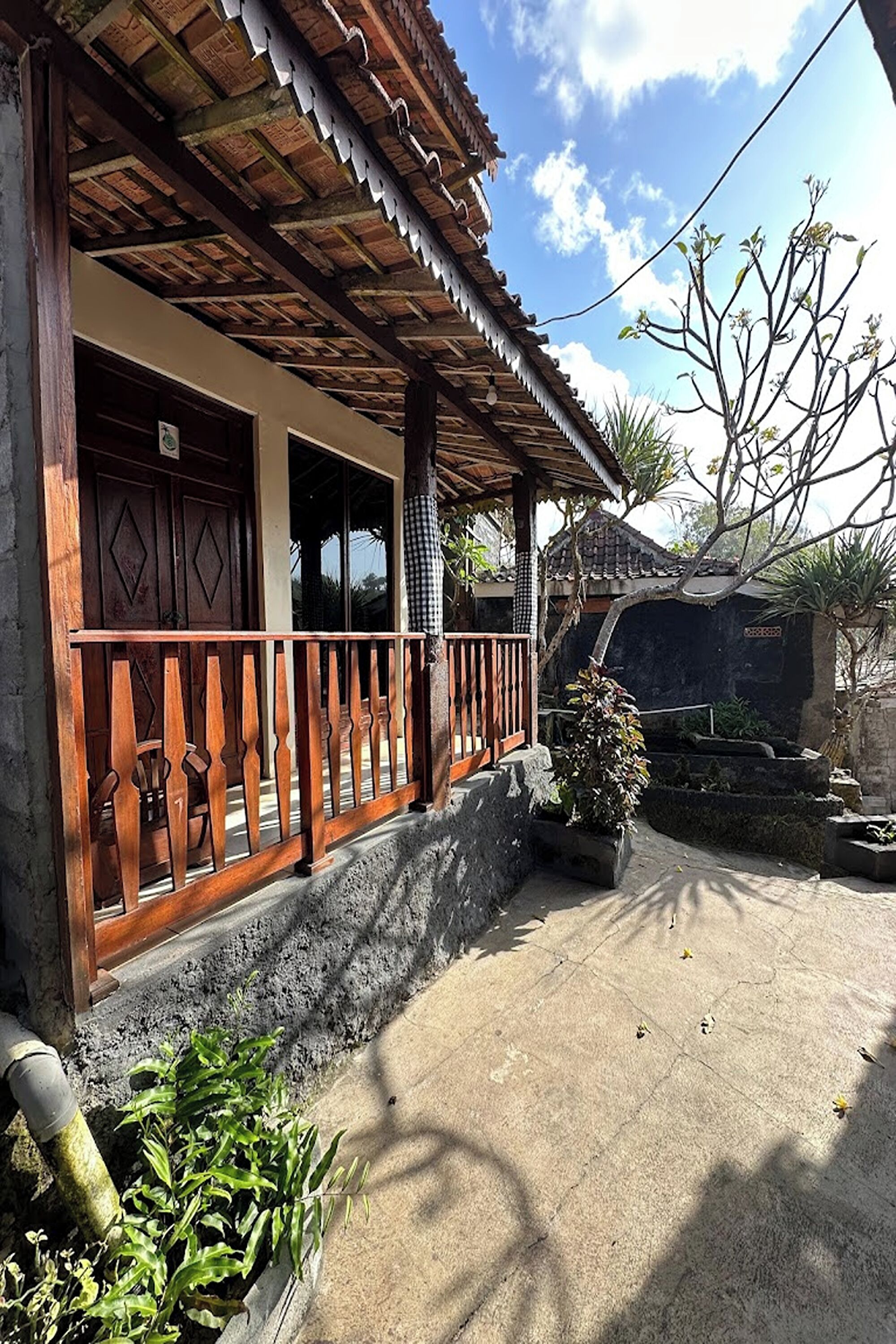 Uma casa tradicional com varanda de madeira, telhado de telhas e parede de pedra.