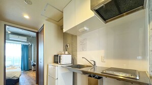 Uma cozinha compacta com micro-ondas, geladeira, pia e um pequeno balcão.