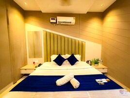 Quarto de hotel com cama, mesa de cabeceira, ar condicionado fixado na parede e um pequeno vaso de planta.