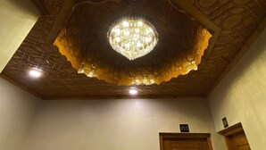 Quarto com teto em padrão hexagonal e lustre central.