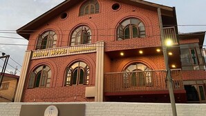 Um edifício de vários andares com fachada de tijolos, janelas em arco e uma placa com o nome 'Willow Woods'.