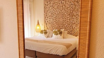 Quarto com um espelho grande, uma cama, um painel decorativo na parede e um abajur.