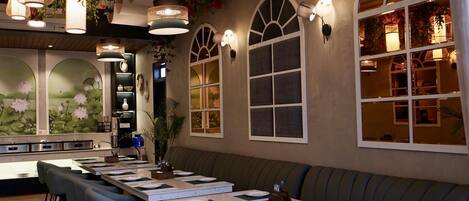 Um restaurante com um balcão comprido, cadeiras azuis e chão estampado.