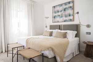 Um quarto moderno com uma cama grande, duas mesas de cabeceira, um abajur e um quadro na parede.