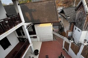 Edifício residencial com vários andares, área externa coberta, escada e pátio cercado.