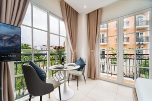 Uma varanda com uma mesa de jantar e cadeiras, uma televisão e cortinas.
